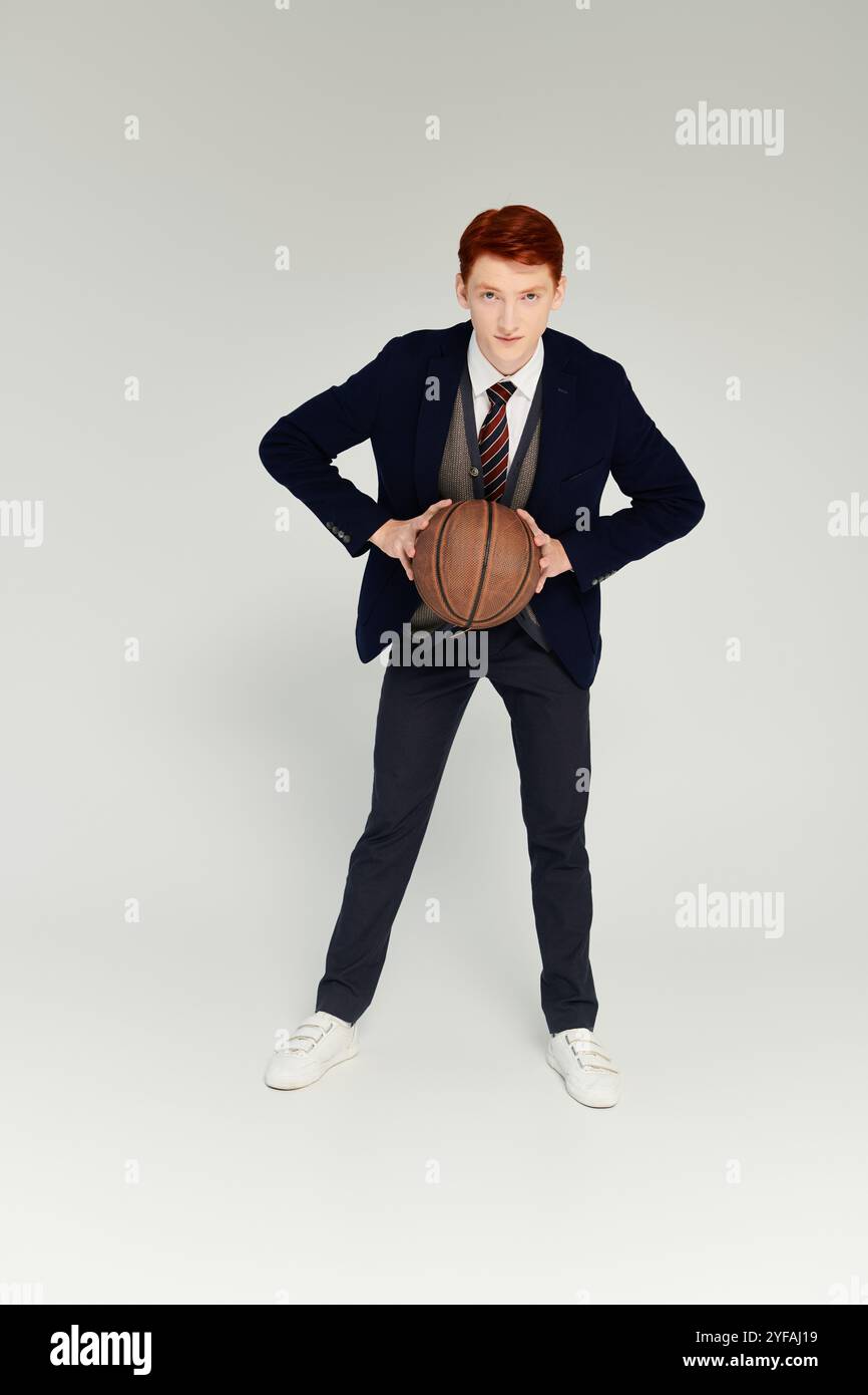 A fashionable young man with red hair poses confidently in a studio ...
