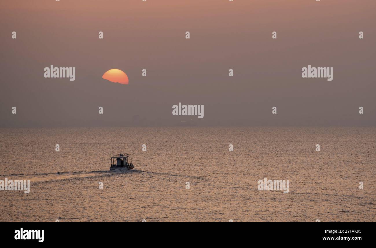 Fishing boat sailing in the sea to catch fish at sunset. Bright sun ...