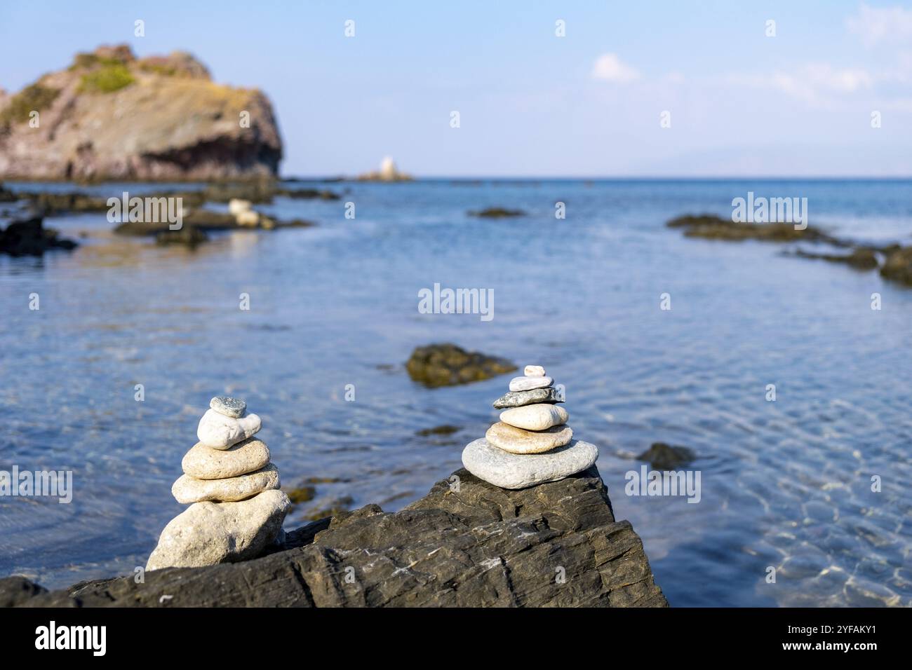 Pyramid of balancing white pebbles, on the rock of a rocky beach ...