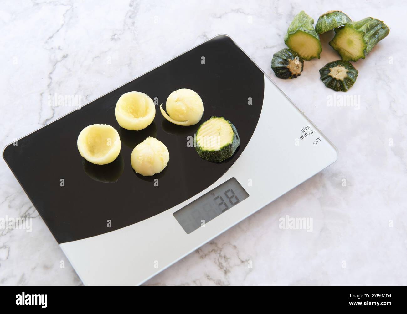Fresh slices of zucchini raw vegetable on a weigh scale. Healthy low ...