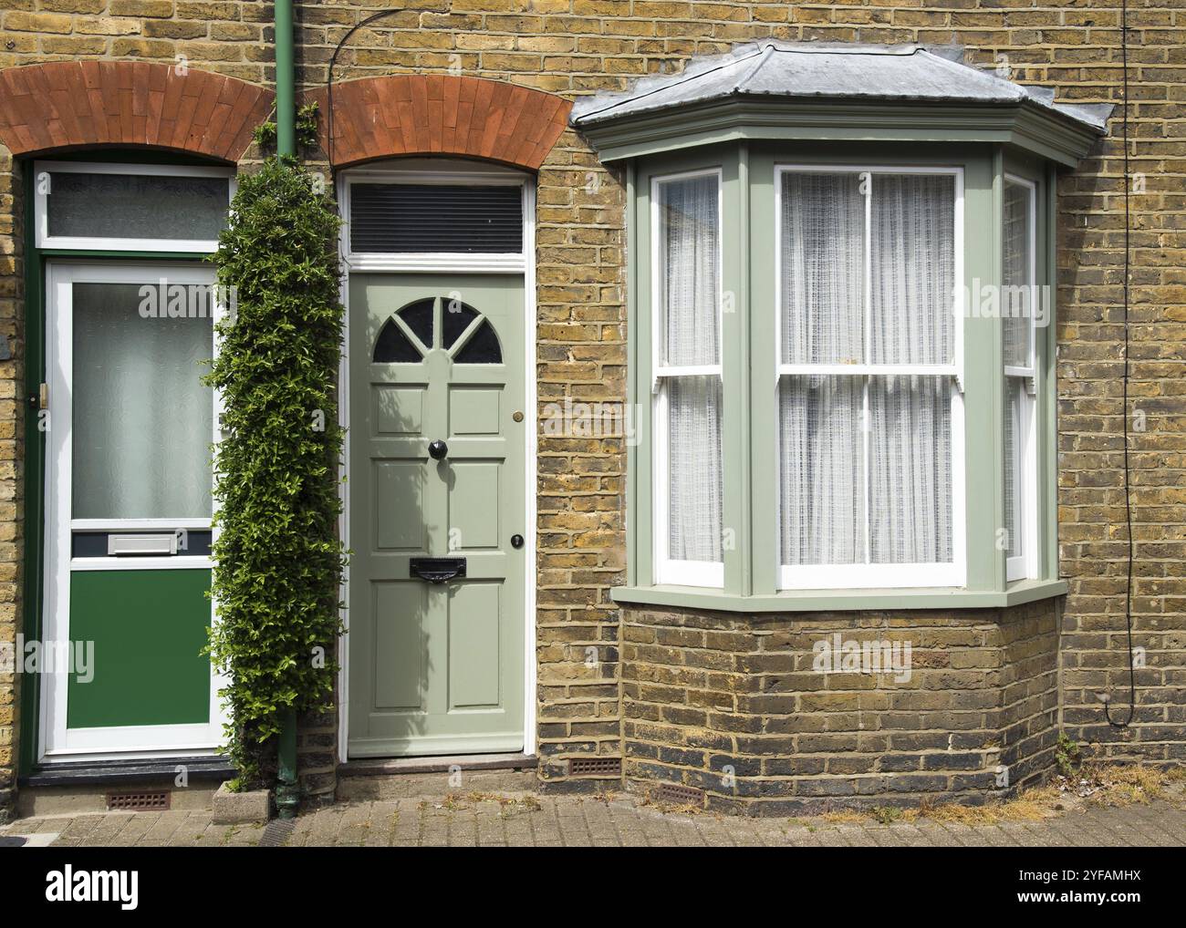 Traditional English house front entrance with green closed doors and ...