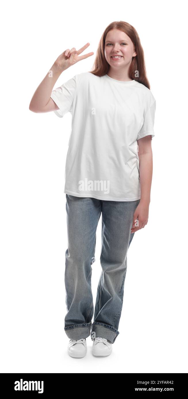 Teenage girl showing v-sign on white background Stock Photo - Alamy