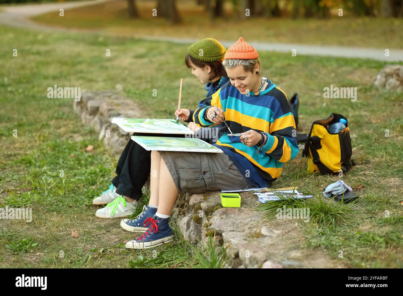 two young and innovative female artists conducting an outdoor painting ...