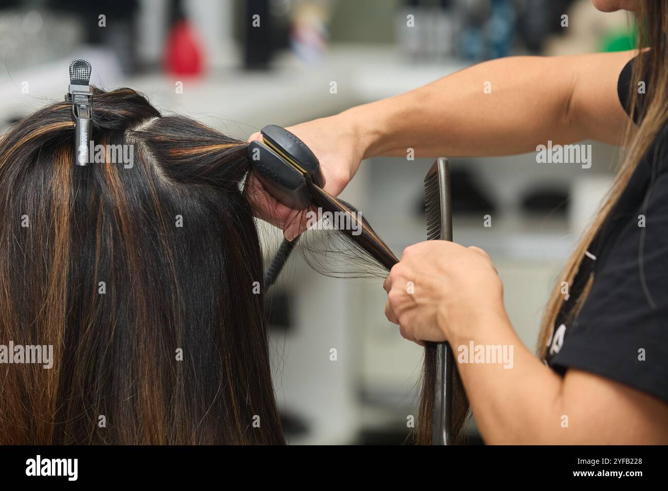 A young hair stylist prepares to apply color to a young woman's hair ...