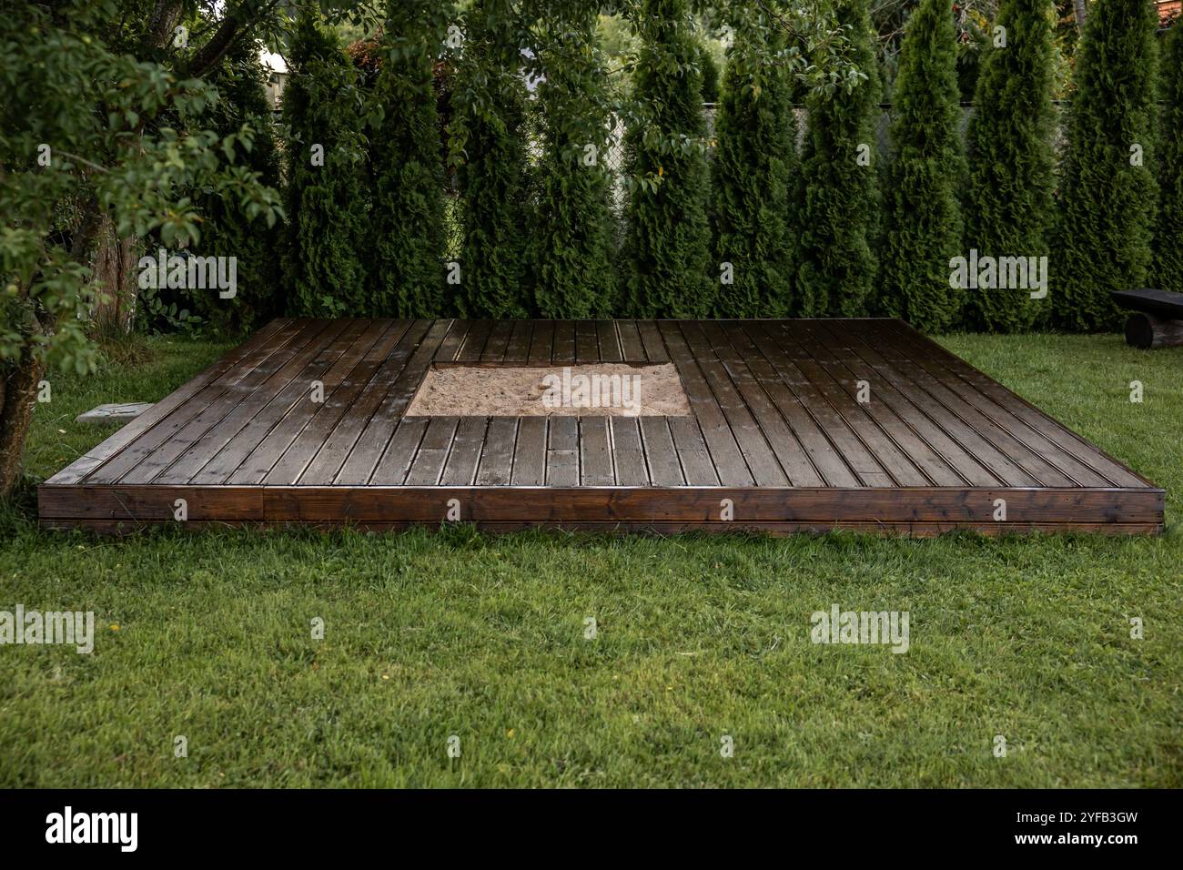 Wooden deck with central sandpit in a backyard setting, surrounded by ...
