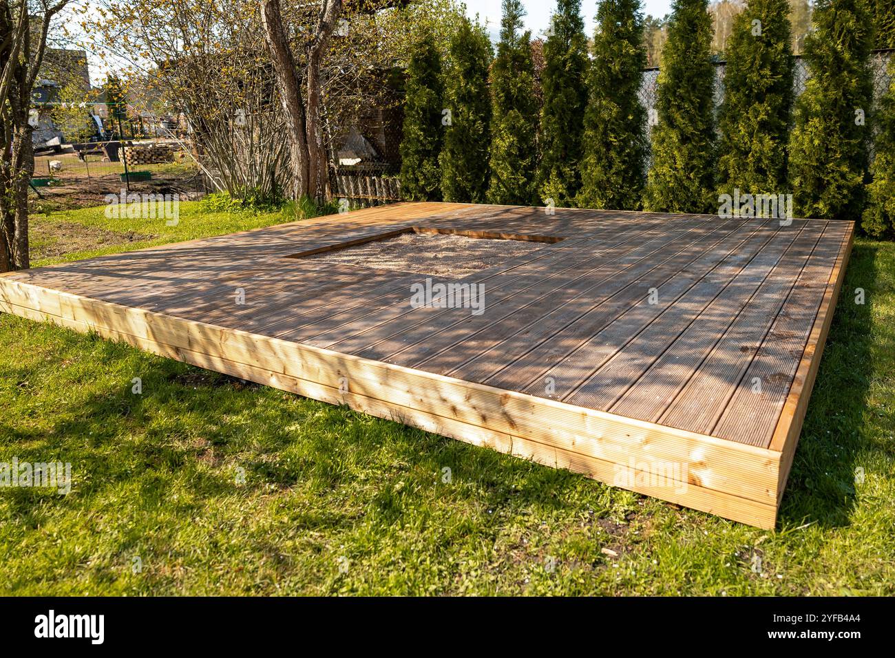 Wooden deck with central sandpit in a backyard setting, surrounded by ...