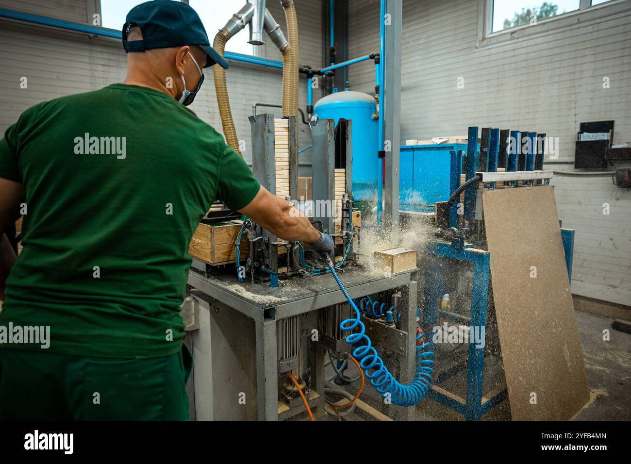 Worker operating machinery in a woodworking factory, focusing on ...