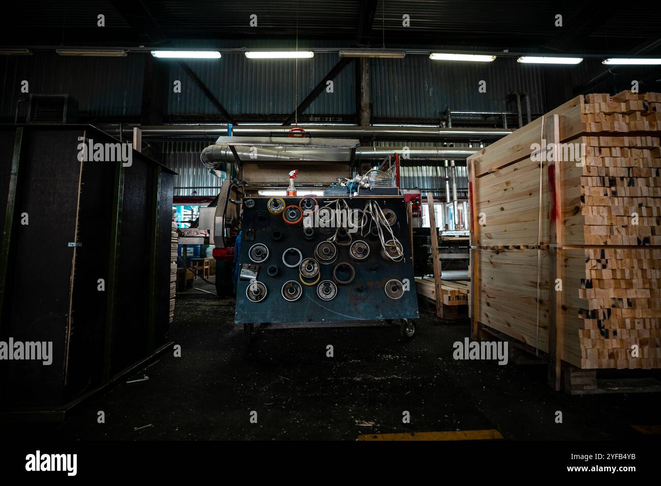 An industrial machine surrounded by stacked wooden materials ...