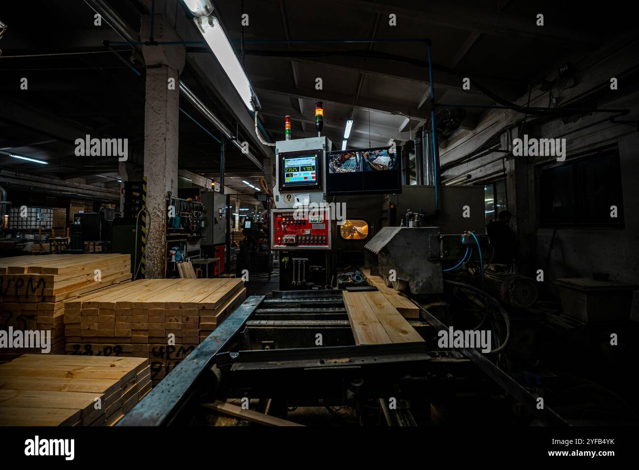 A dimly lit woodworking factory featuring stacks of cut timber, an ...
