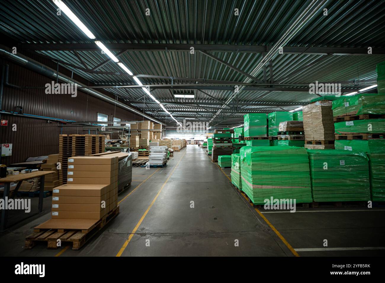 A large woodworking factory with stacks of freshly cut timber panels ...