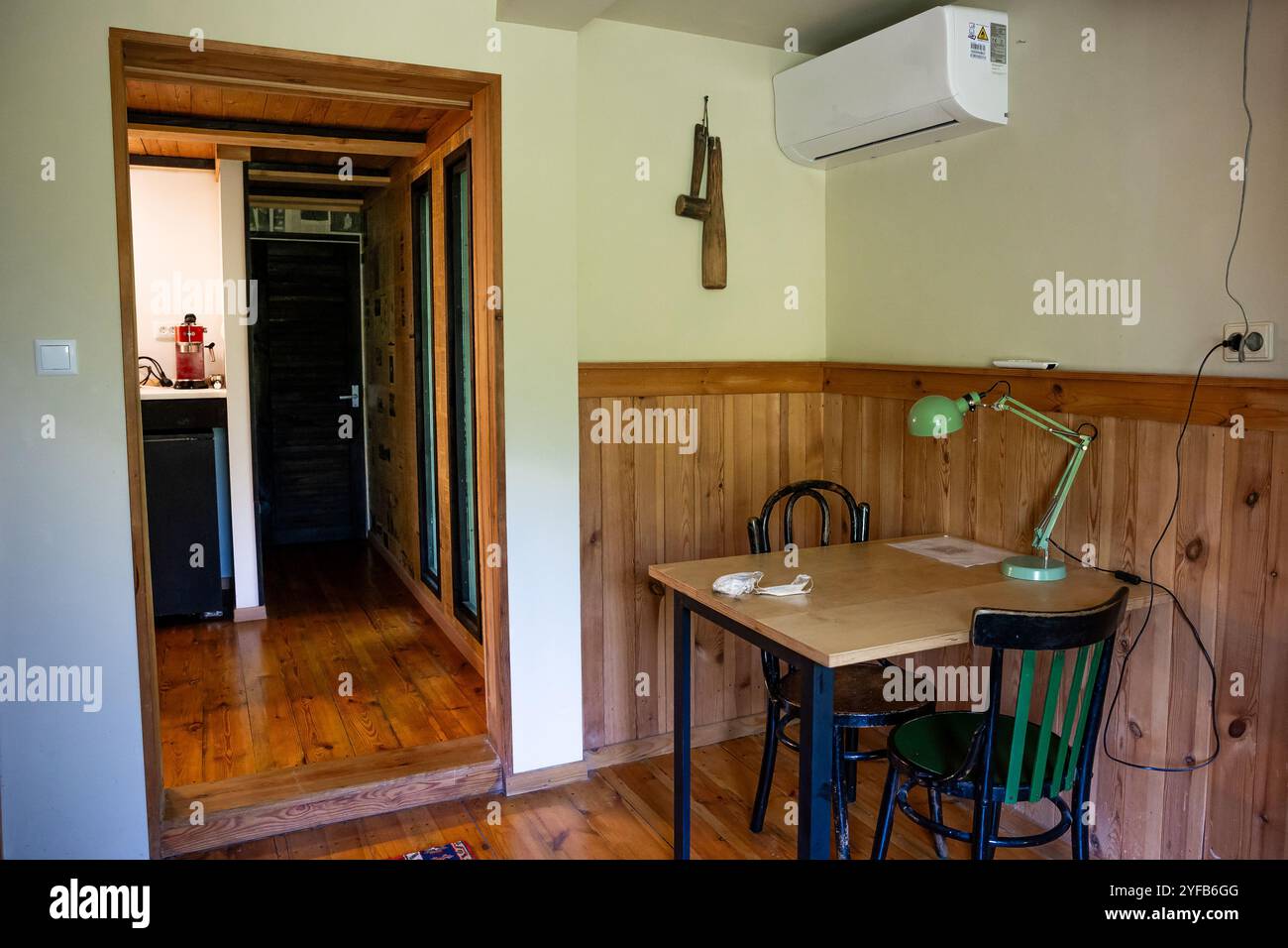 Small workspace inside a rustic cabin with a wooden desk, chairs, and ...