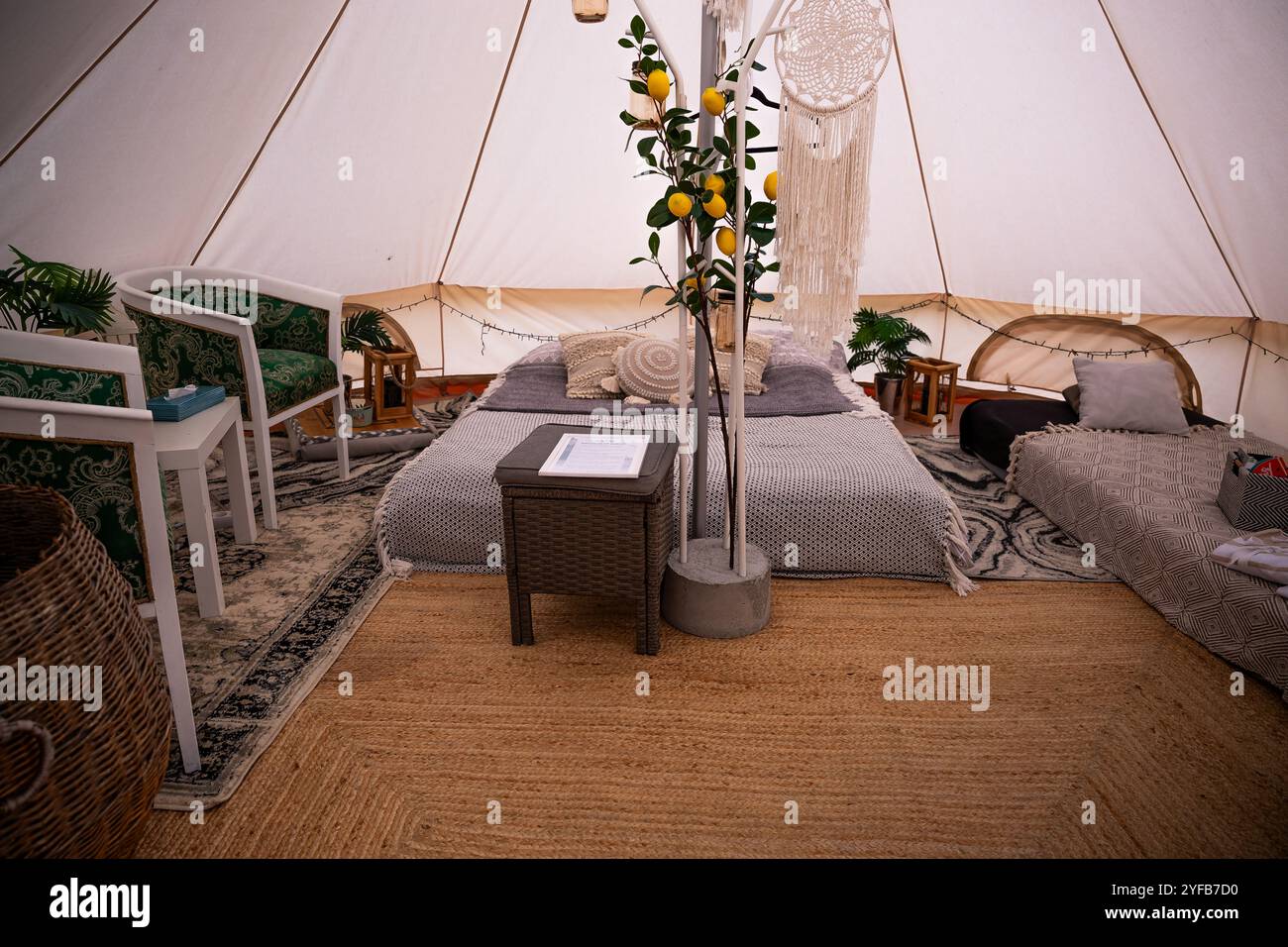 Cozy interior of a glamping tent with a large bed, woven rugs, chairs ...