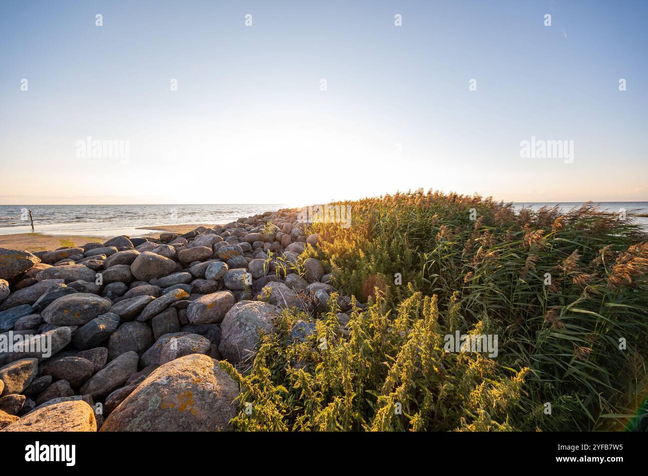 Sunset view of a narrow rocky path leading into the water, with the sky ...