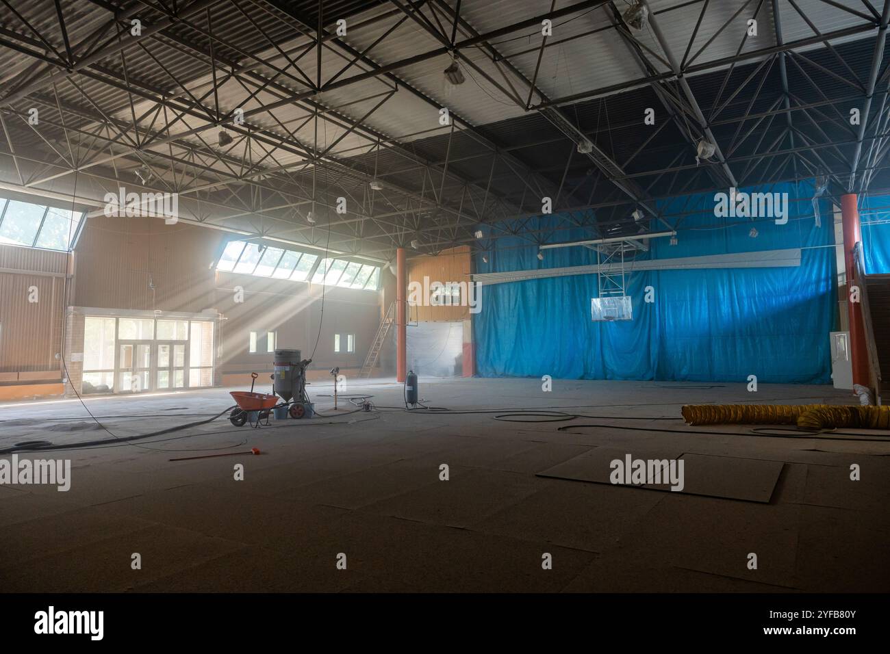 Indoor gym under construction with covered floors, scaffolding, and ...