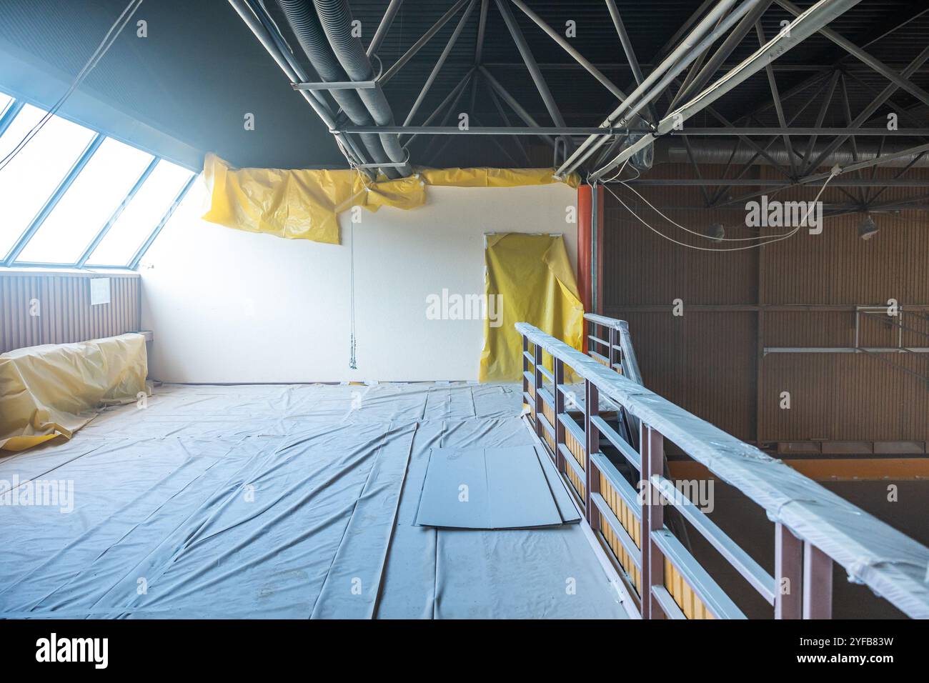 Large indoor gym with high ceilings, covered floors, and construction ...