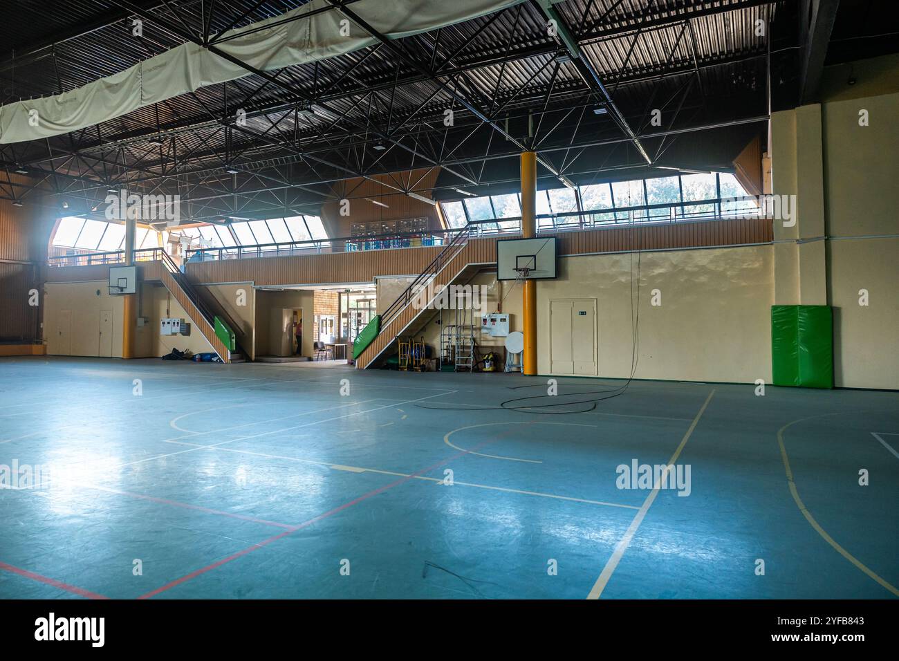 Indoor basketball court with high ceilings, sunlight streaming through ...