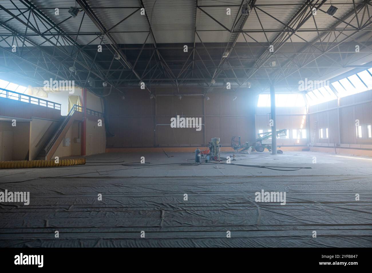 Gym under renovation with construction equipment, covered floors, and ...