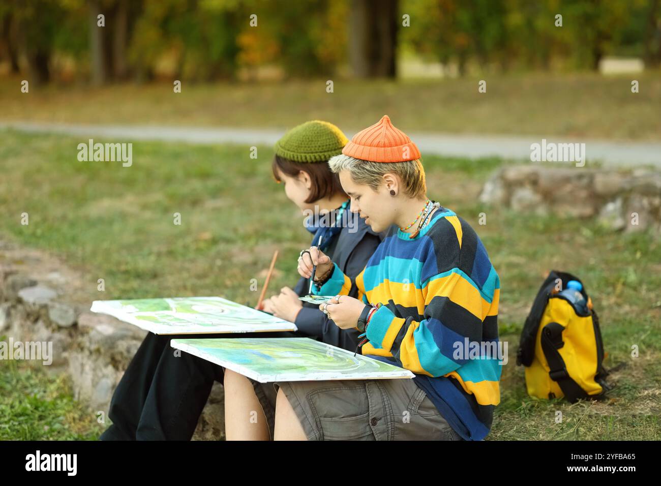 two young and innovative female artists conducting an outdoor painting ...