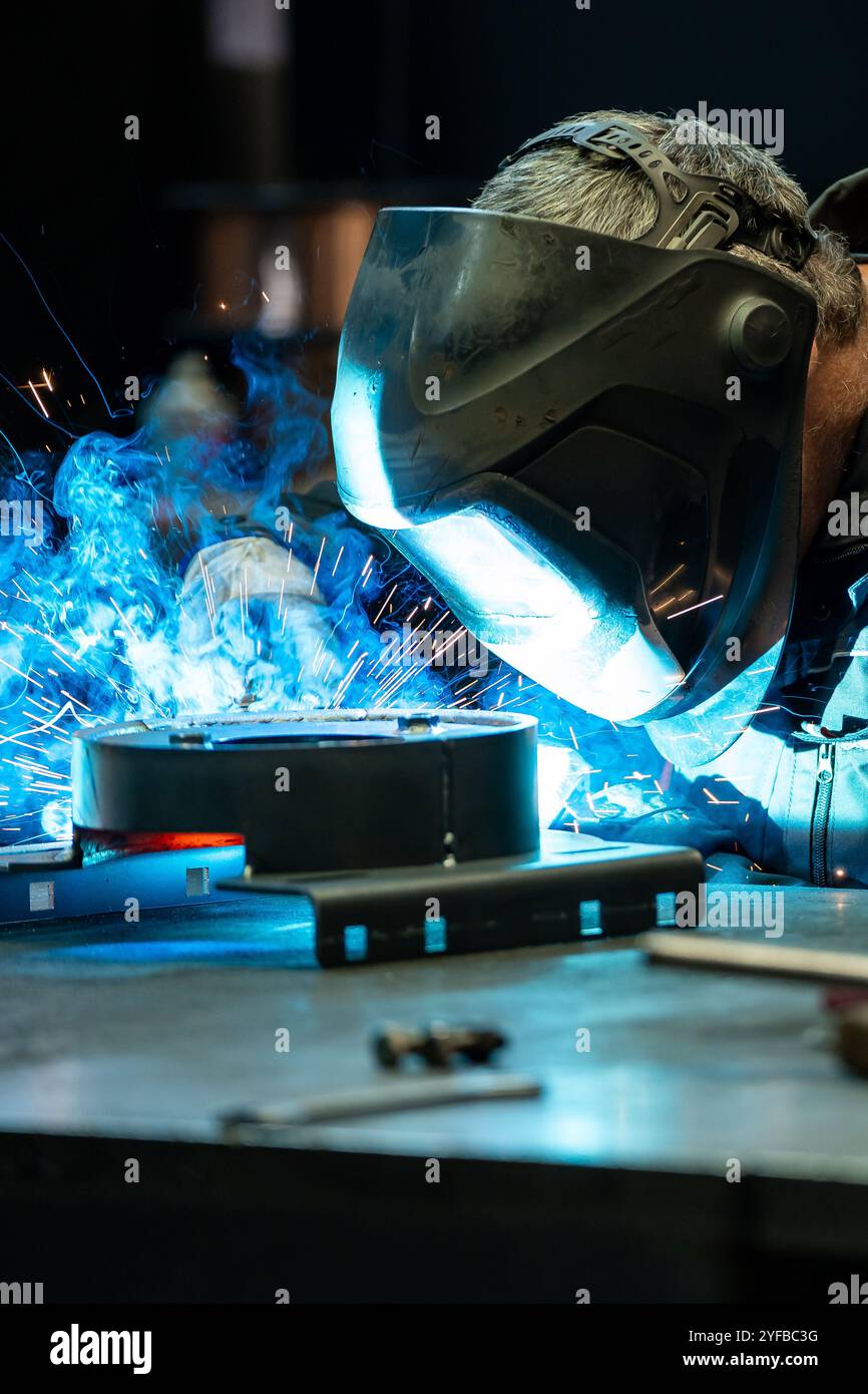Close-up of a welder focused on his work, bright blue light and sparks ...