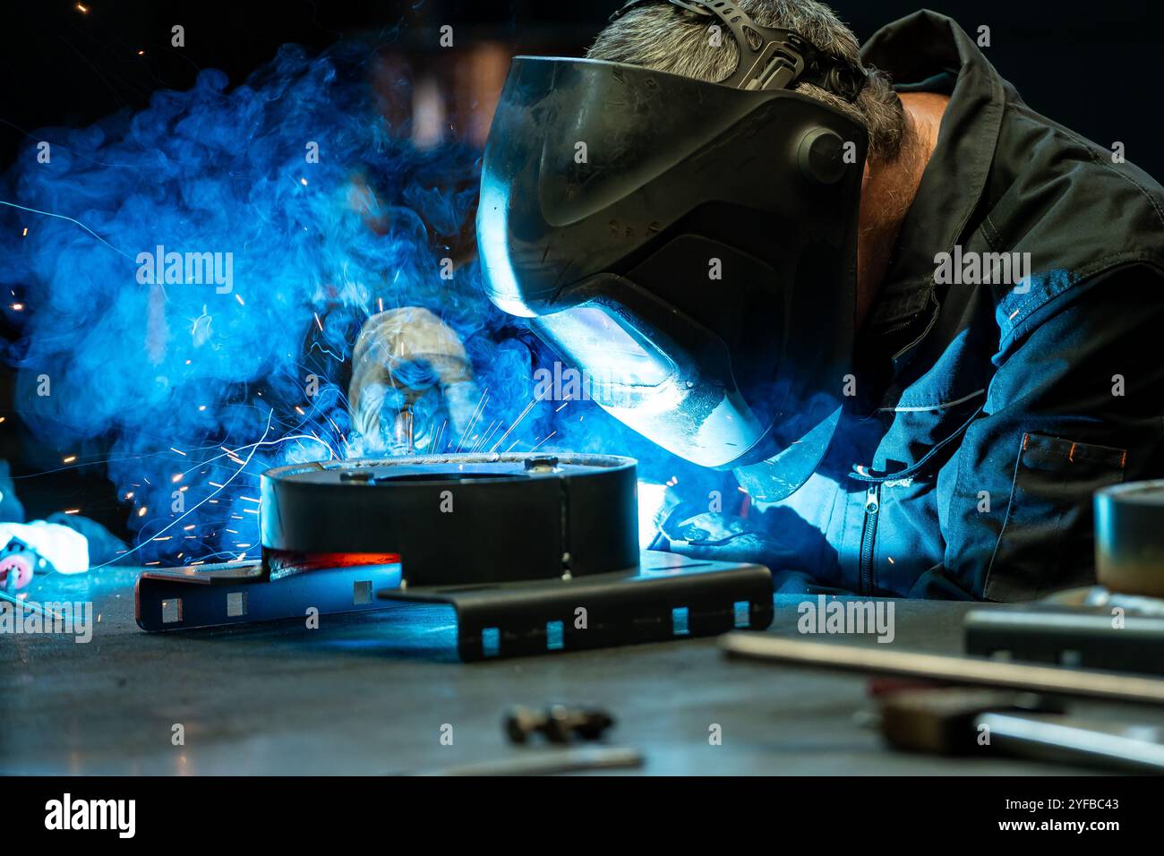 Close-up of a welder focused on his work, bright blue light and sparks ...