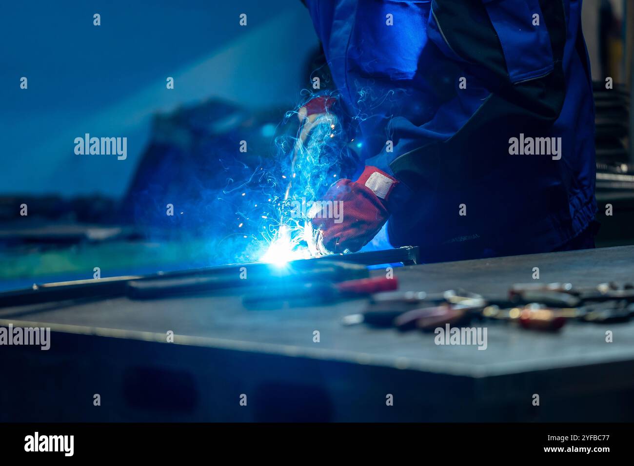 Welder using a torch, bright blue flame and sparks in a workshop ...