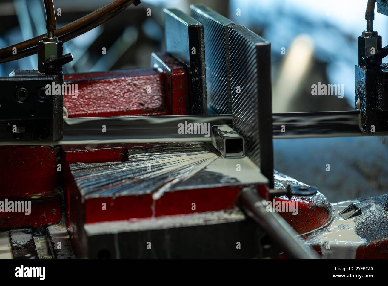 Detailed view of a red metalworking machine in a factory, cutting a ...
