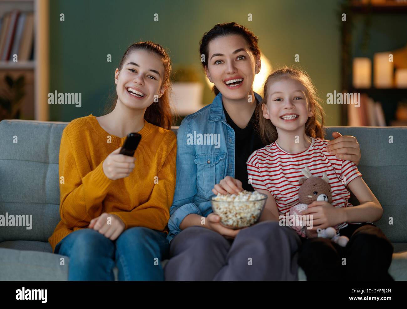 Happy family watching projector, TV, movies with popcorn in the evening ...