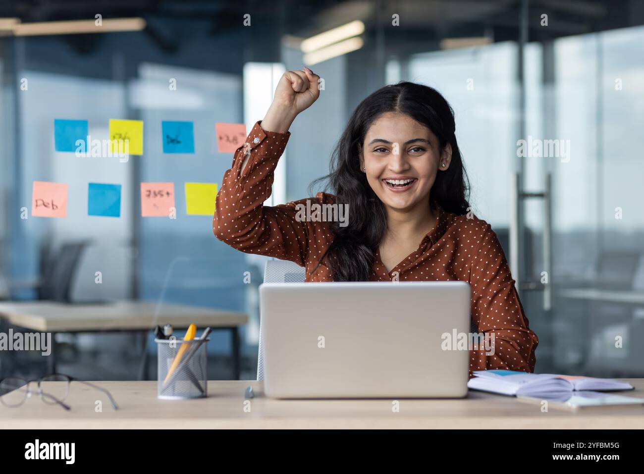Young hispanic business woman celebrating success at work using laptop ...