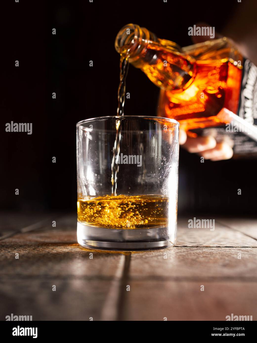 A close-up shot of whiskey being poured into a glass, showcasing the ...