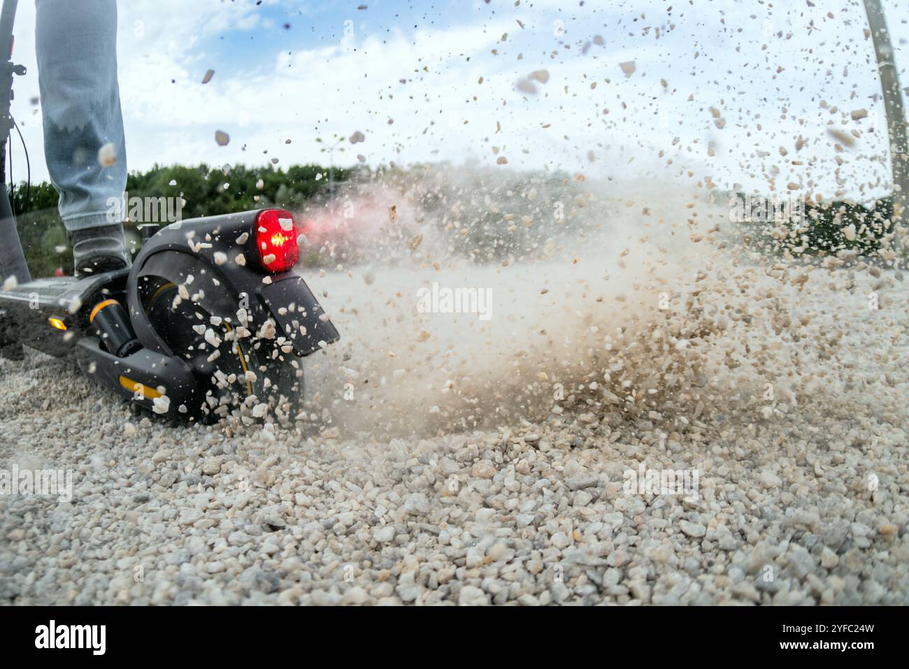 Starting a scooter on a gravel road with slipping and flying stones ...