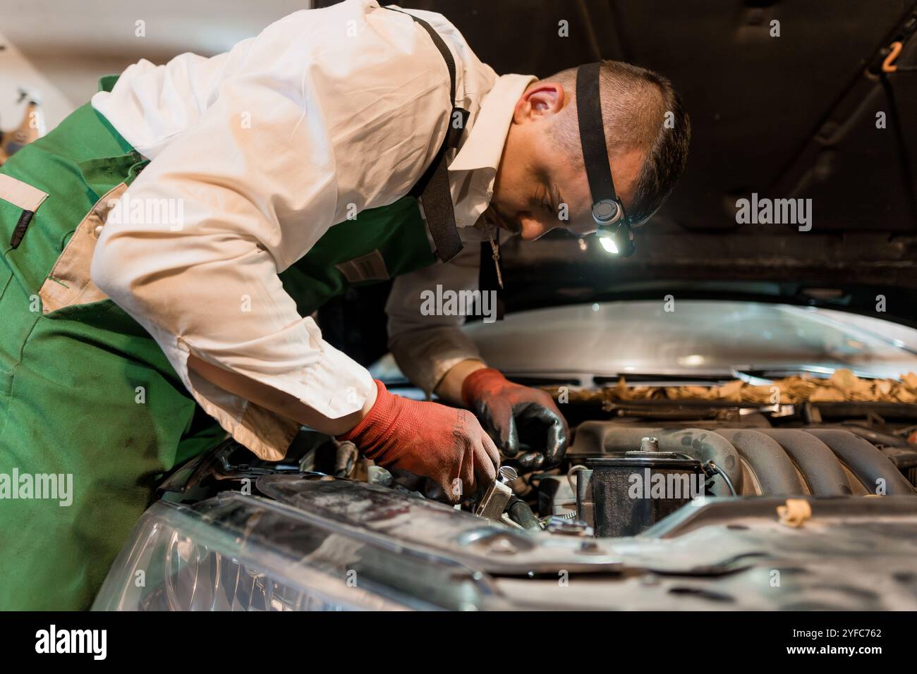 Mechanic Performing Maintenance on a Car Engine with Focus and ...