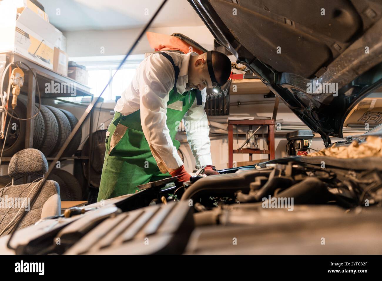 Mechanic Performing Repairs Inside a Garage with Tools and Equipment ...