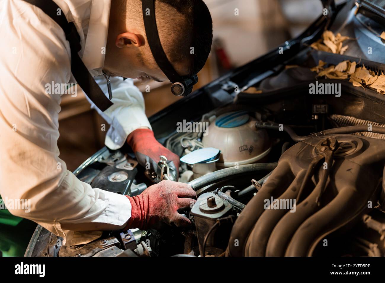 Mechanic Working Diligently on a Car Engine in a Garage Stock Photo - Alamy