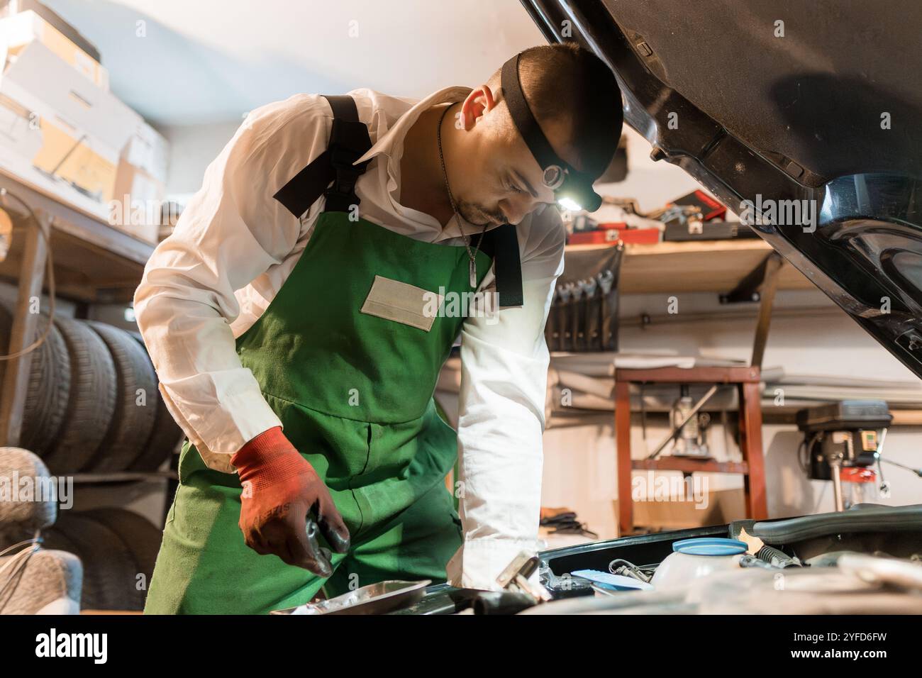Mechanic in Green Overalls Working on Car Engine with Headlamp Stock ...