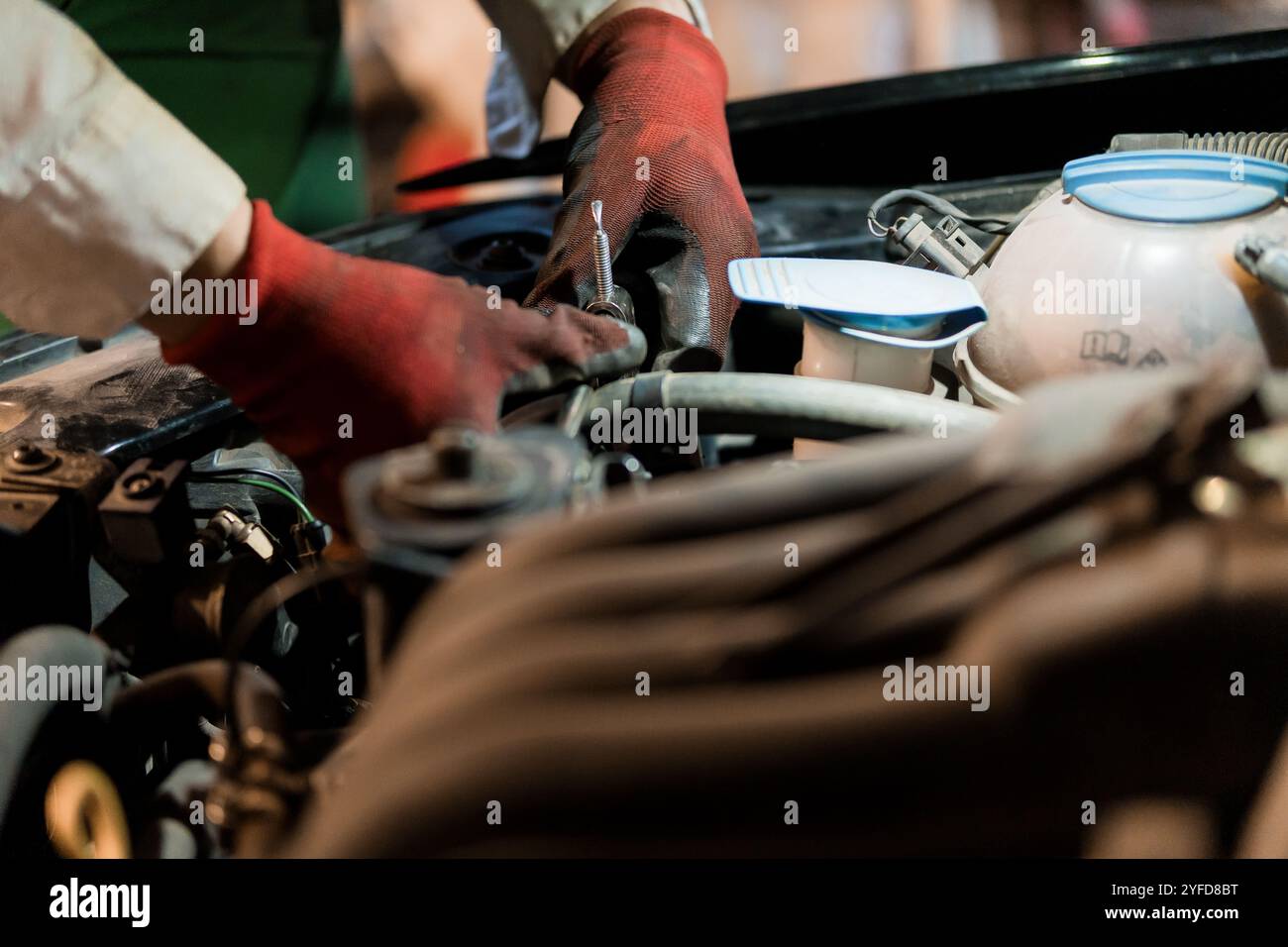 Mechanic Performing Maintenance on a Car Engine Under Dim Lighting ...
