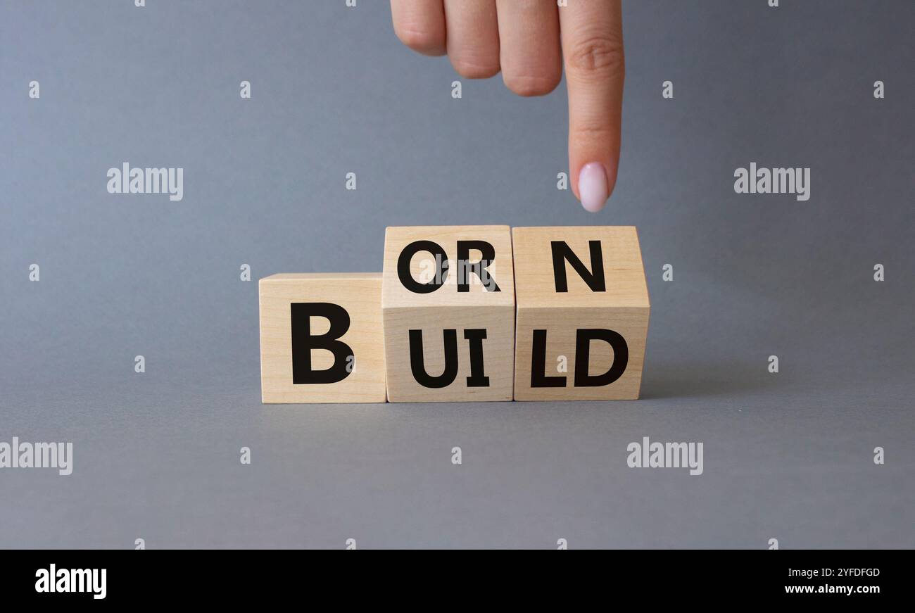 Born and Build symbol. Businessman hand points at turned wooden cubes ...