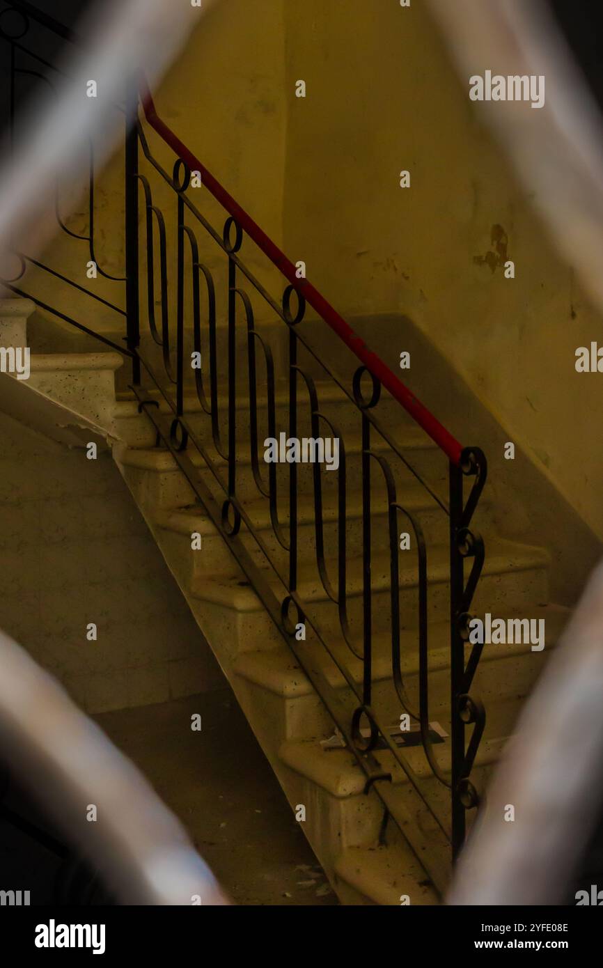 A vintage staircase featuring an ornate metal railing is captured in ...