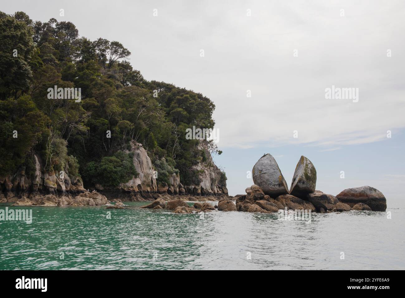 A split boulder creates a unique image along the coast of Abel Tasman ...