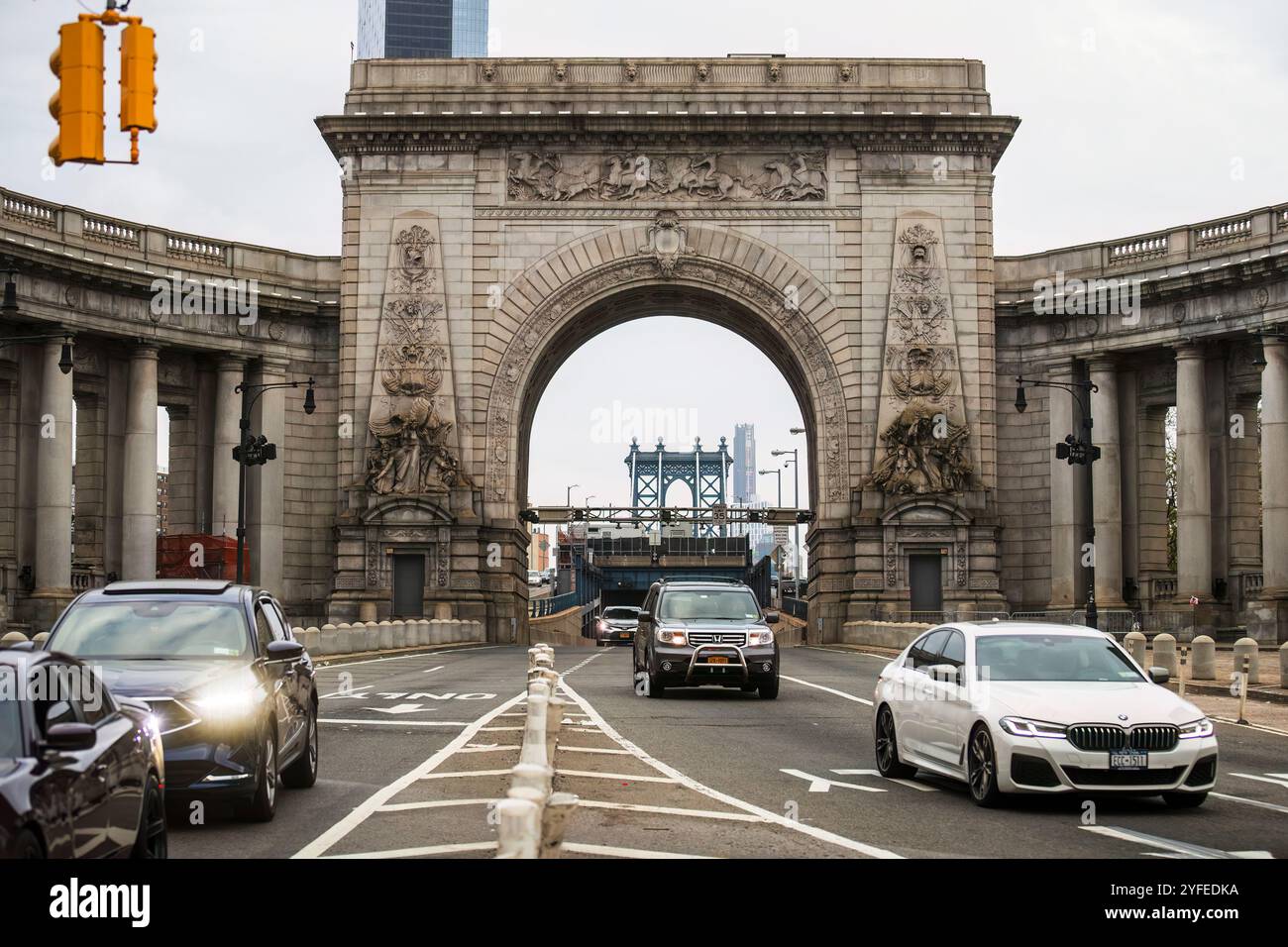 Vehicles drive through the grand arch of the Manhattan Bridge entrance ...