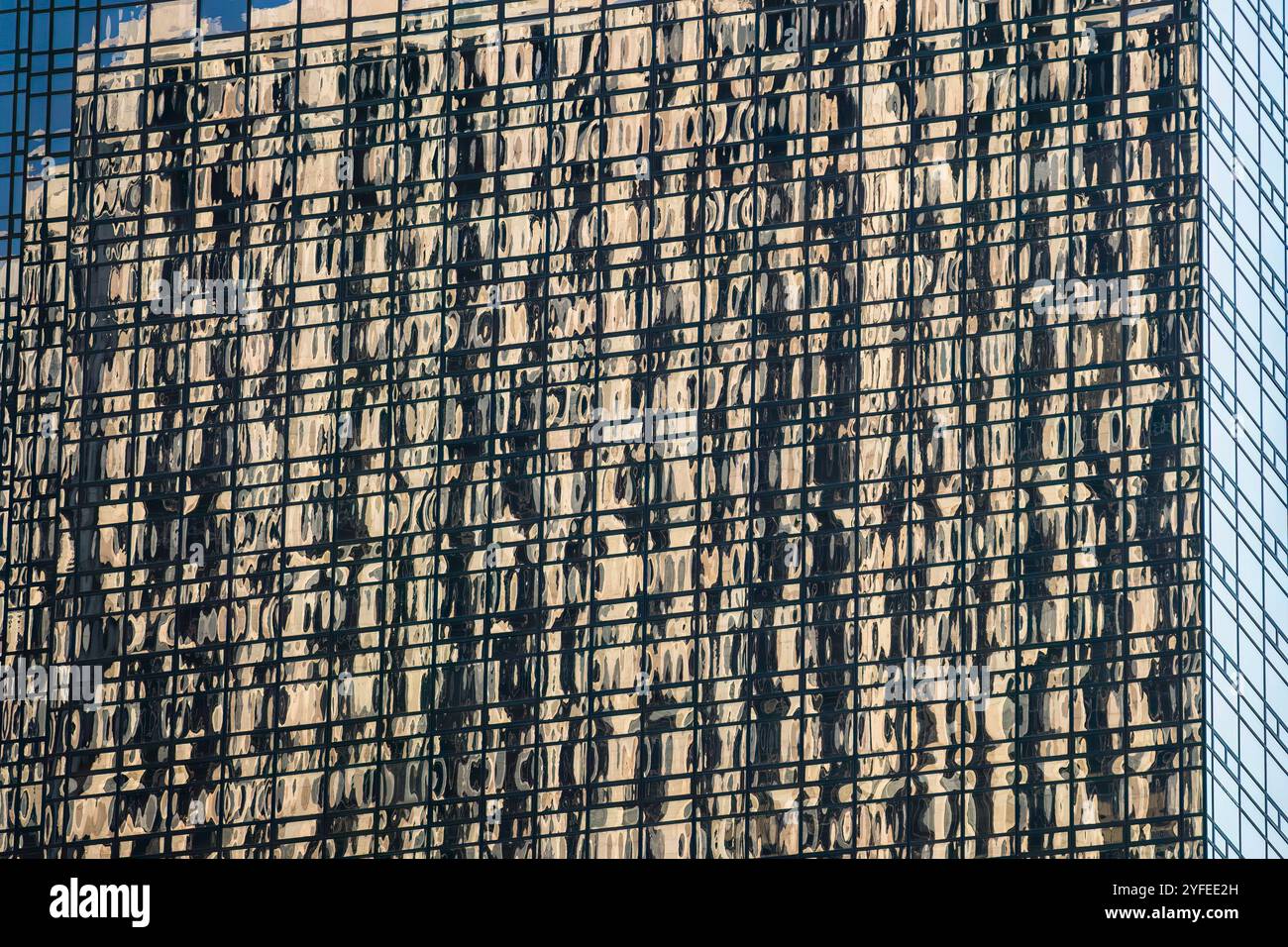A close-up of a glass skyscraper in New York City reflecting distorted ...