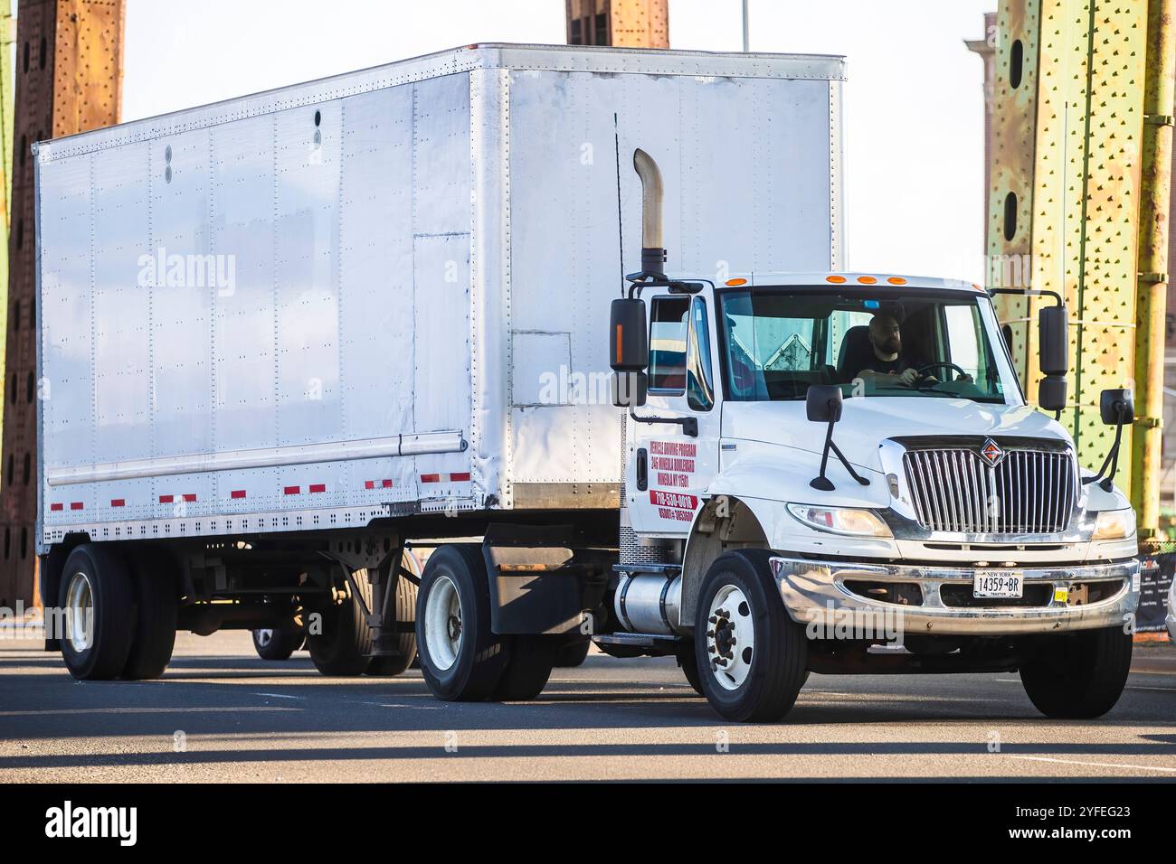White box truck driving across a bridge, carrying cargo in a large ...