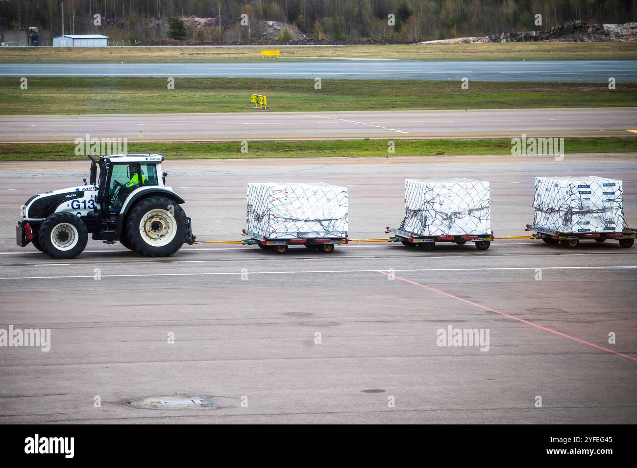Airport tractor towing pallets of cargo on the tarmac Stock Photo - Alamy