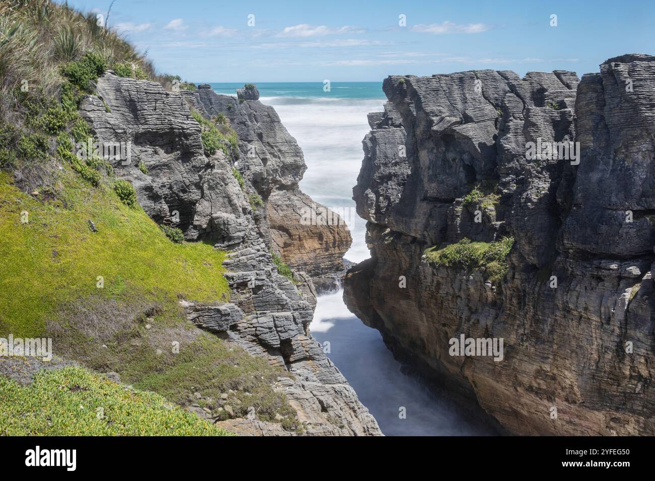 Two steep cliffs with a gap in-between with sea water rushing in Stock ...