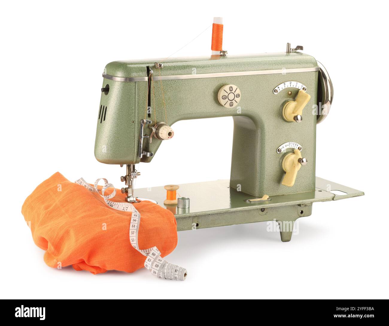 Sewing machine with orange fabric, measuring tape and spools of threads ...