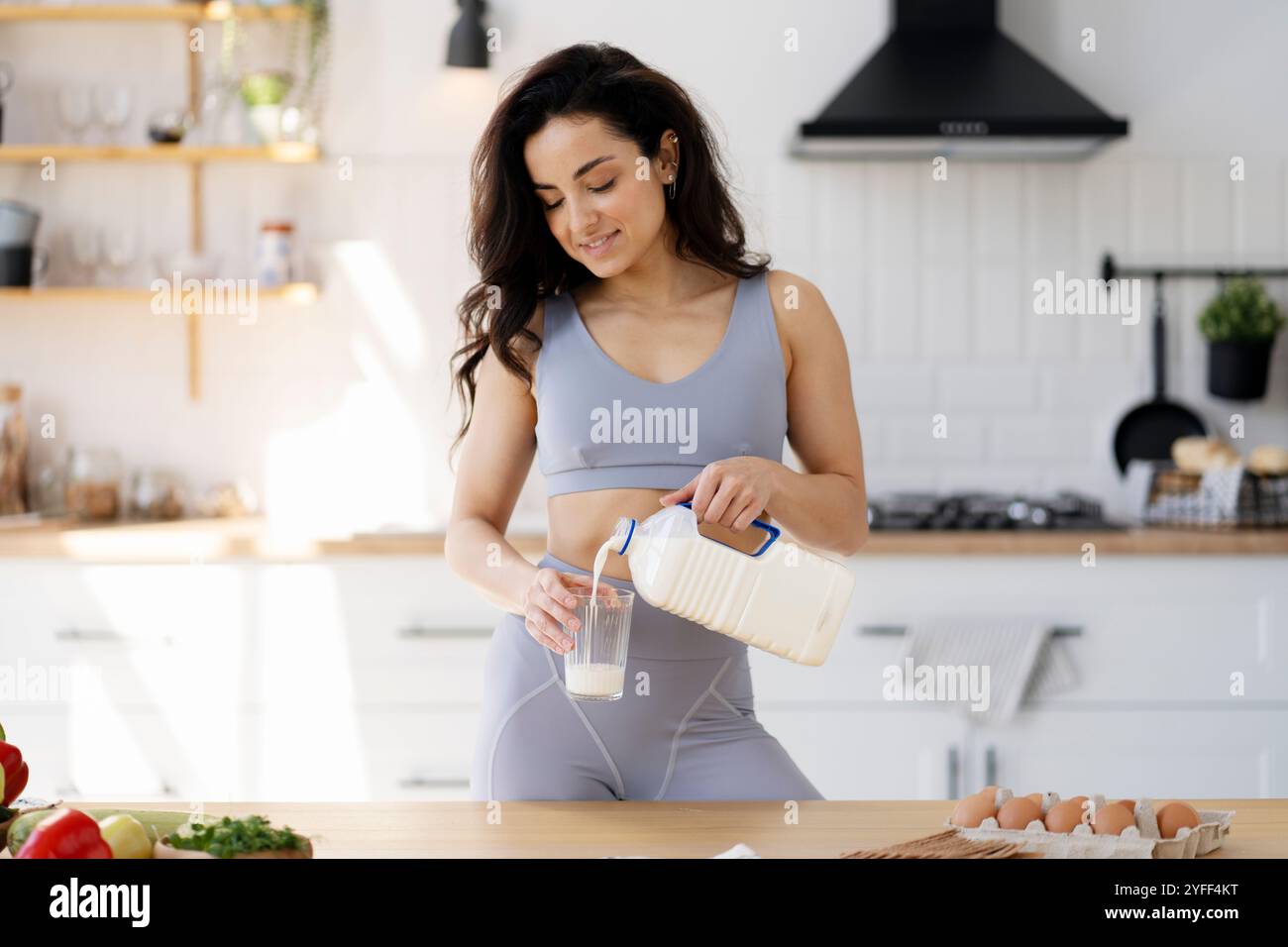 Fitness woman is enjoying a healthy drink in her kitchen after a ...