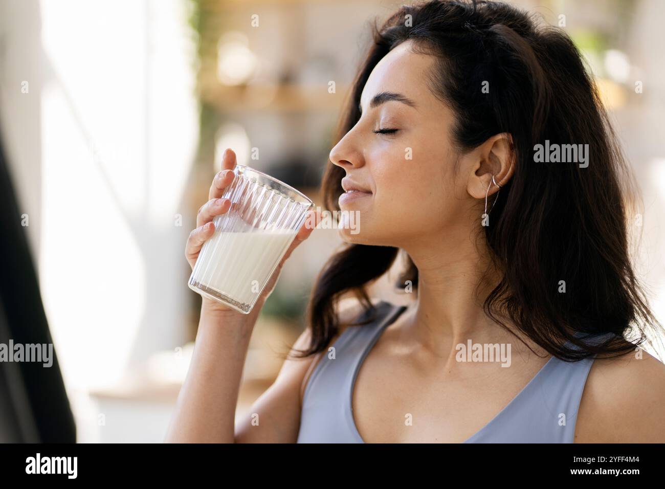 Young woman is holding a glass of milk, her eyes closed as she savors the taste Stock Photo - Alamy