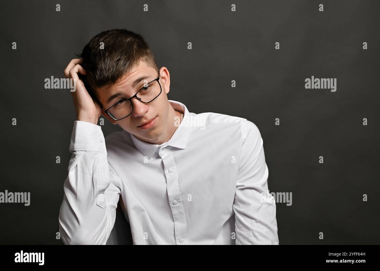 A doubting boy, thinking, scratching his head. on a gray background ...