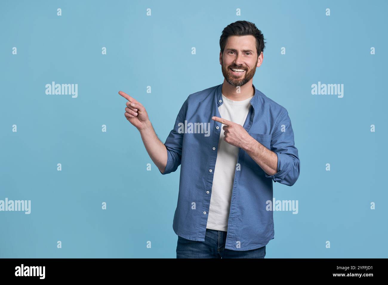 Smiling man pointing his index fingers to the left and right on a blue ...