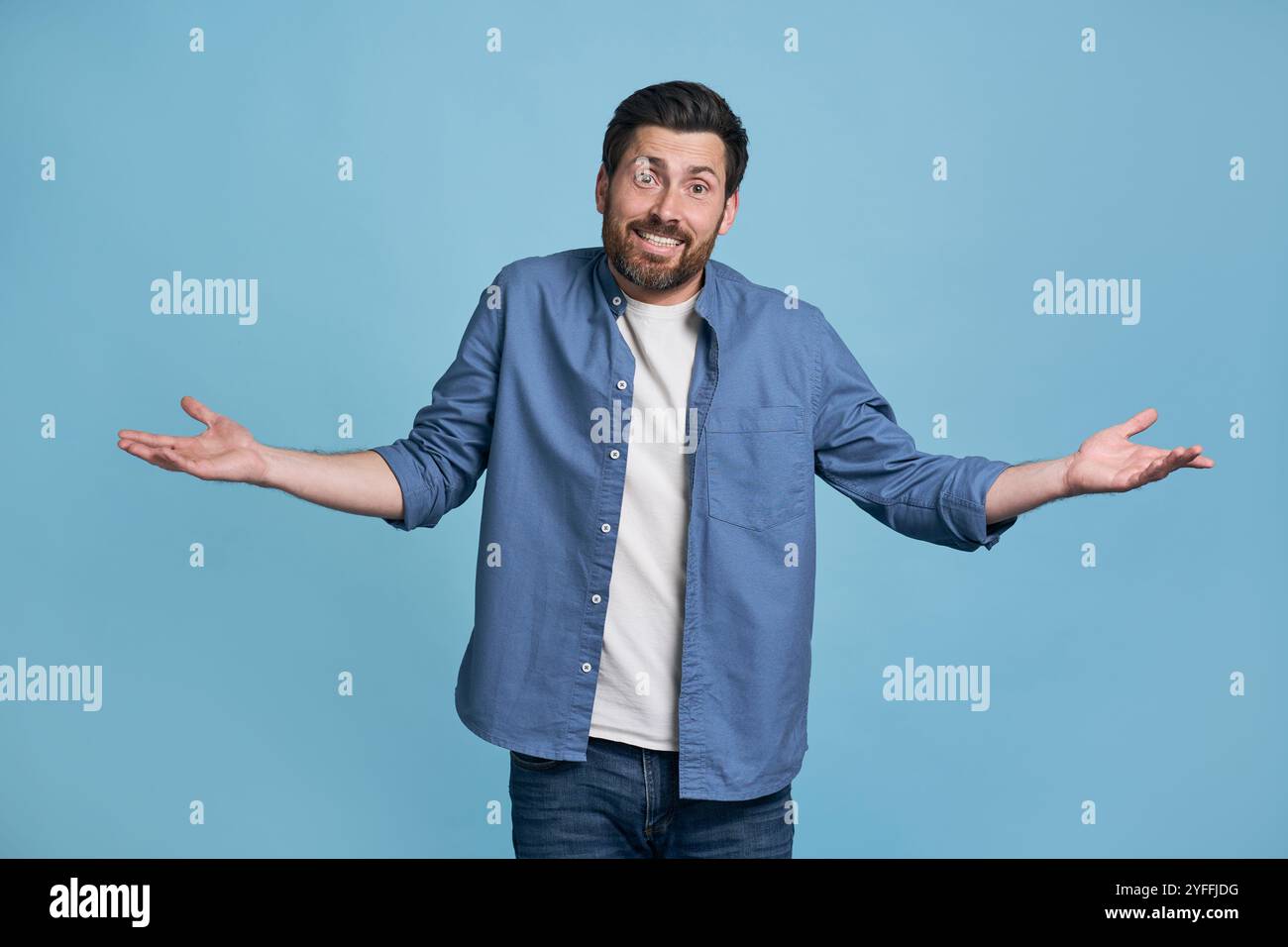 Young man is shrugging his shoulders with his palms up in a gesture of ...