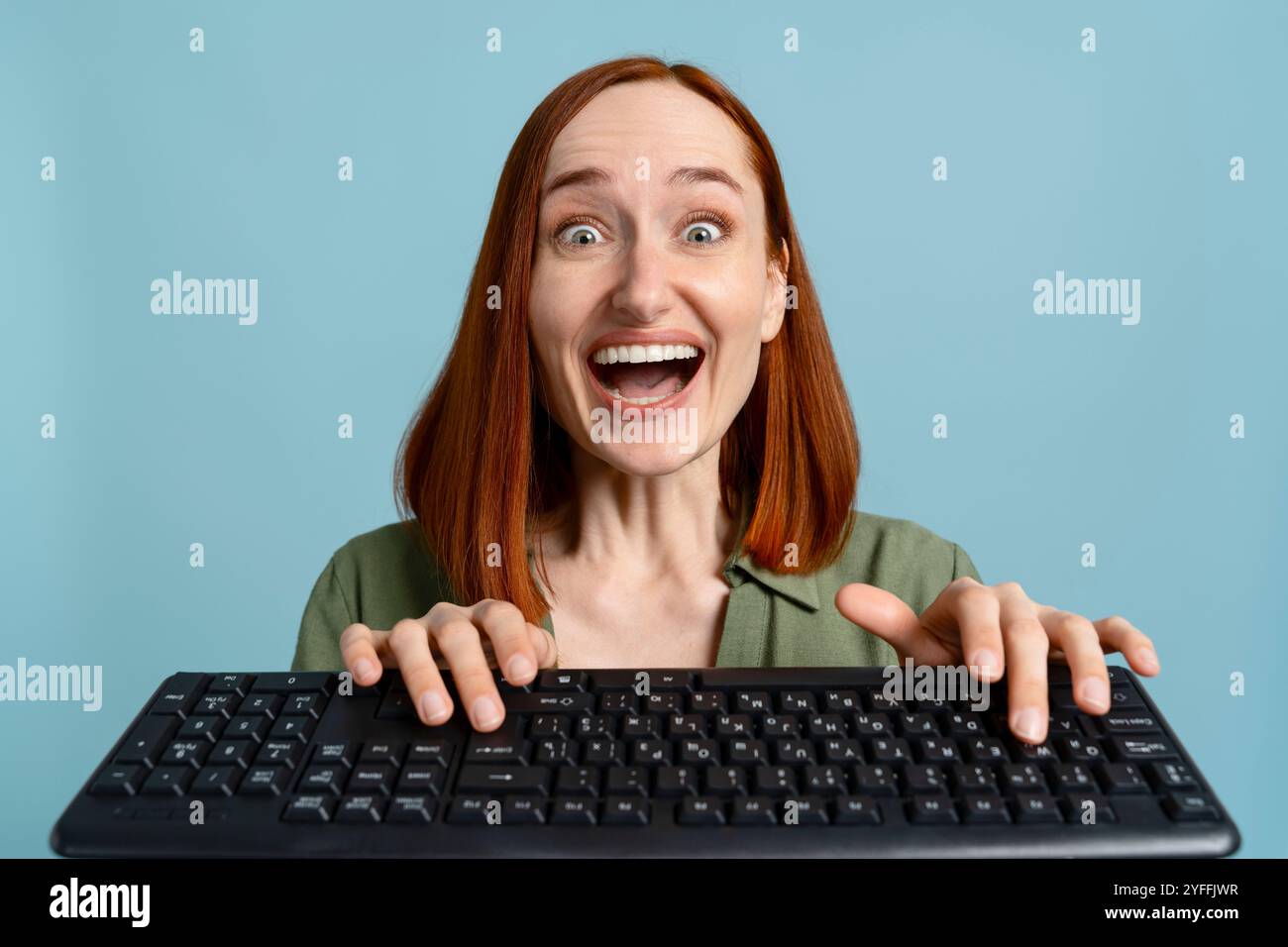 Woman with bright red hair is sitting in front of a computer keyboard ...